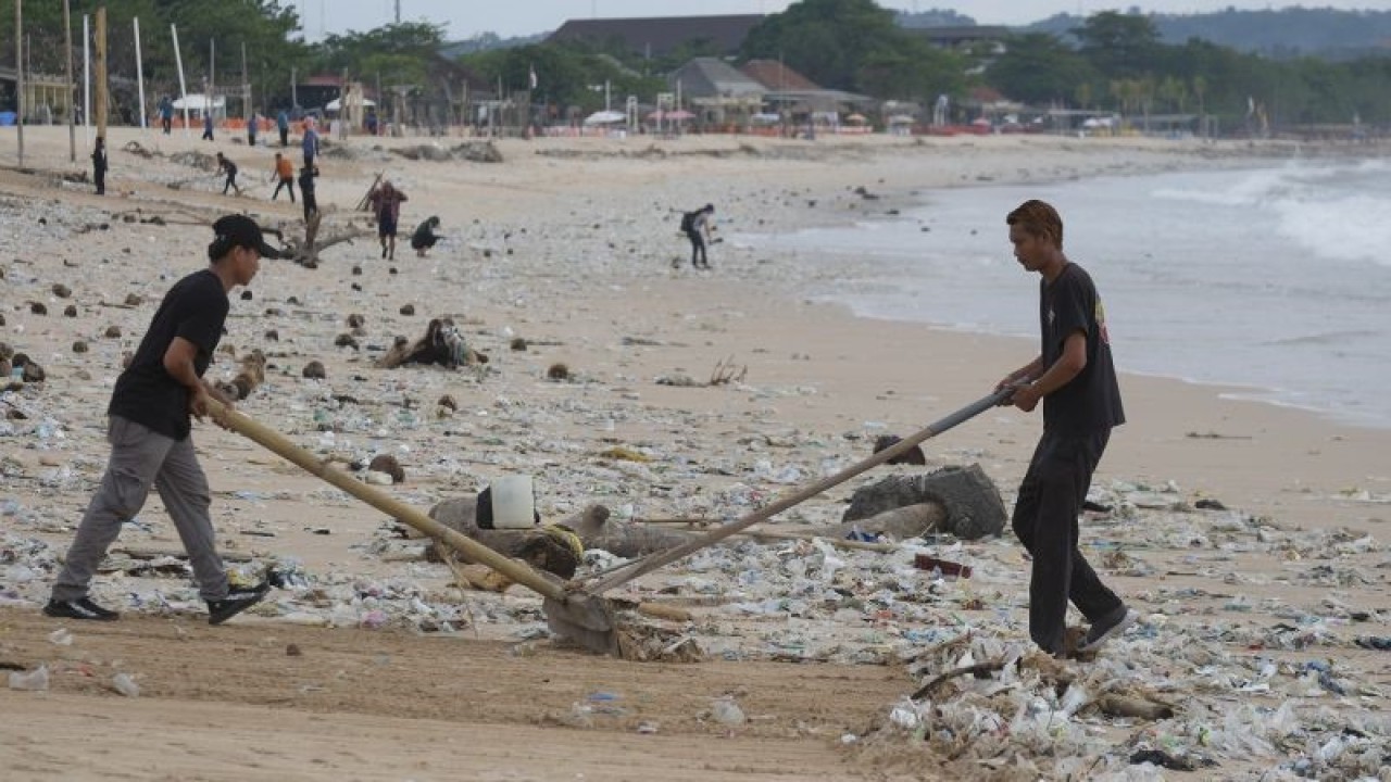 Ilustrasi - Sejumlah pekerja membersihkan sampah terdampar akibat cuaca ekstrem di Pantai ...